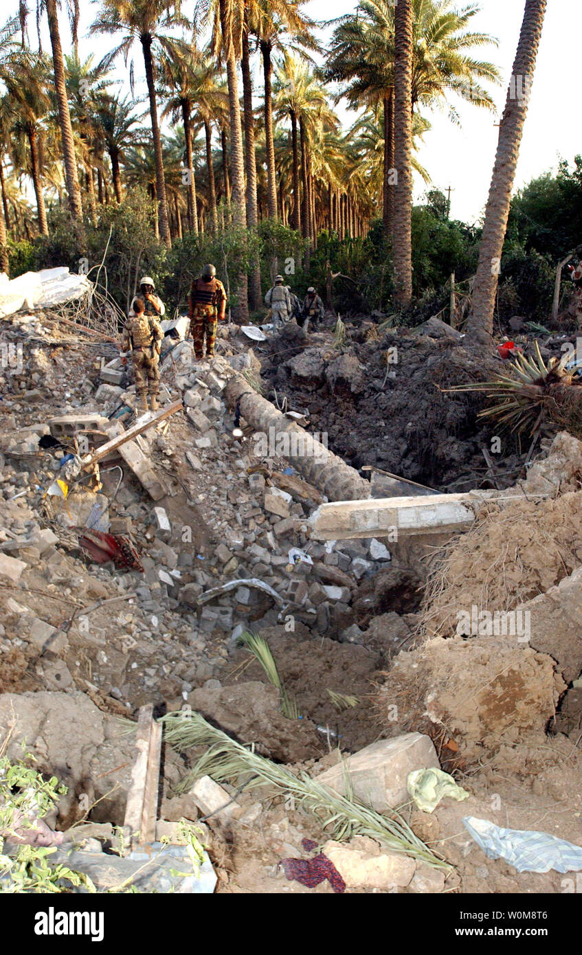 Iraqi and American Soldiers inspect the blast site of an air strike ...