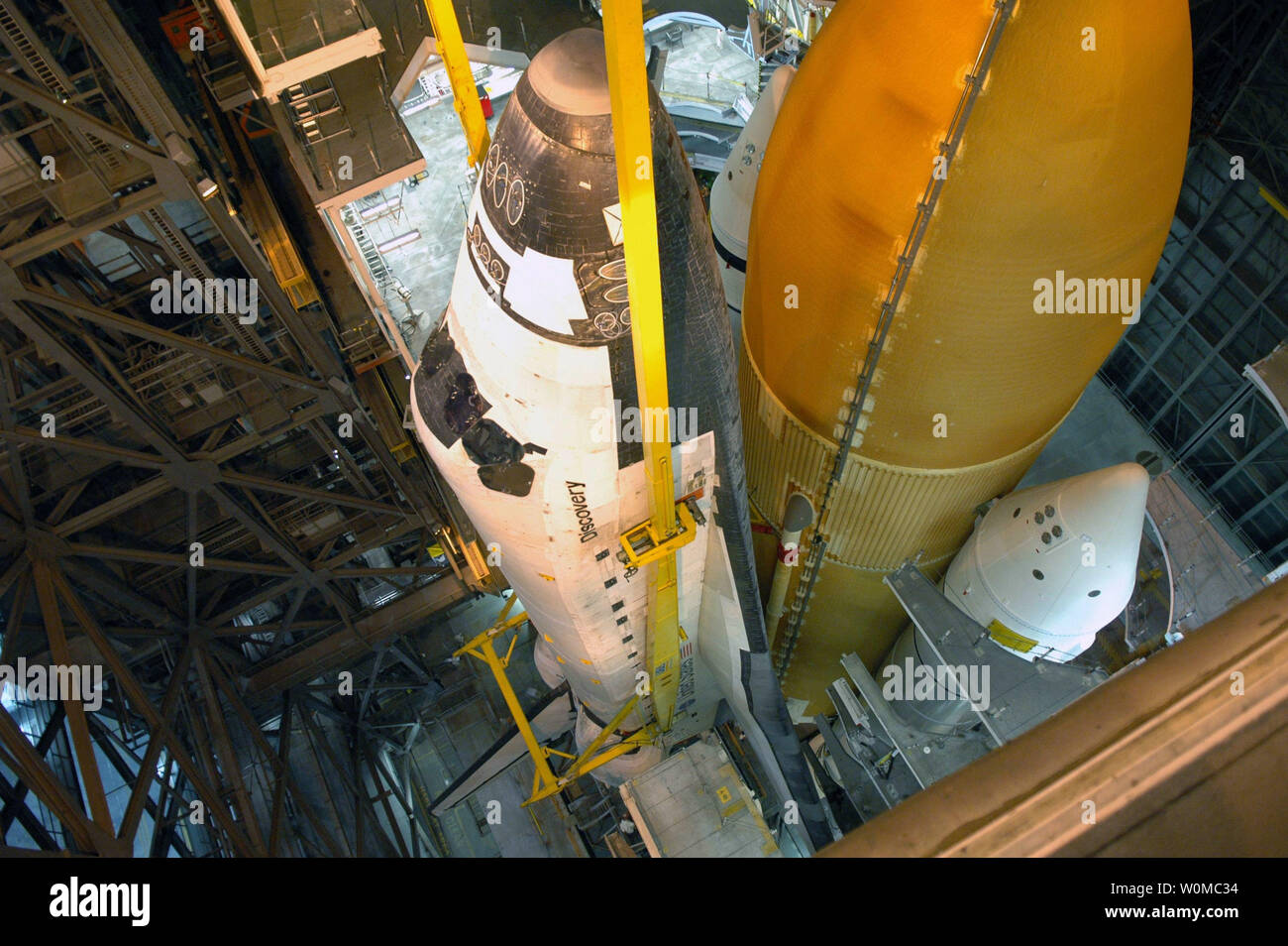Space shuttle Discovery is lowered into position beside its external ...