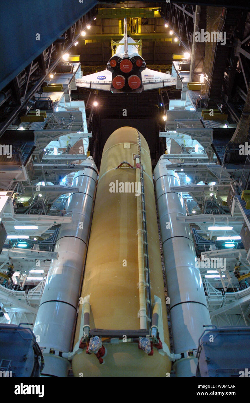 A crane lowers space shuttle Discovery toward the external tank and ...