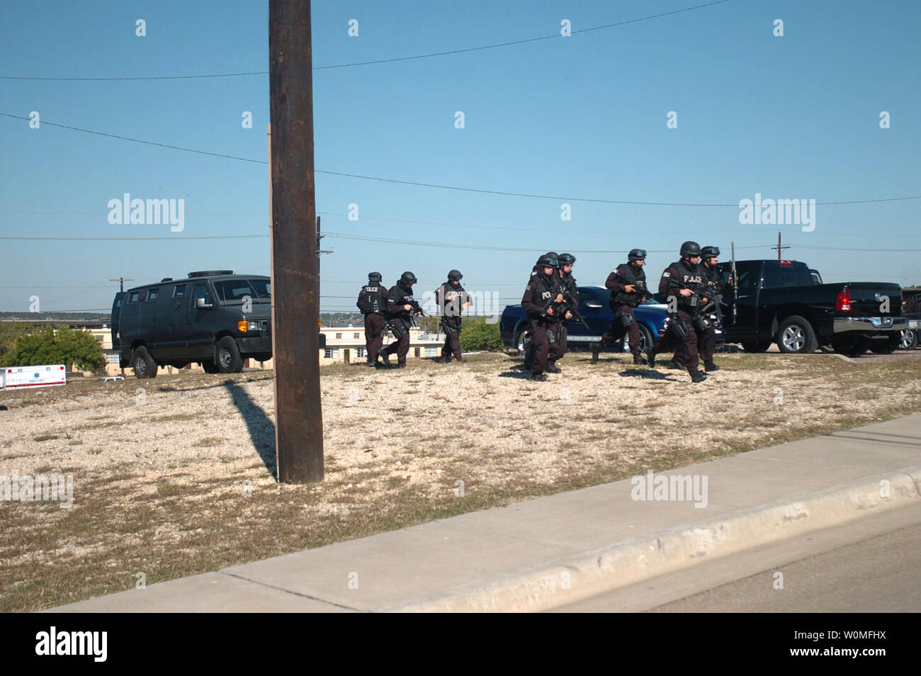 SWAT team members approach a building where a shooter barricaded in the ...