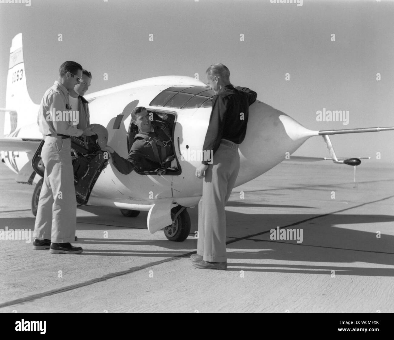 NACA pilot John Griffith (2nd R) hands his flight gear to Dick Payne (L ...