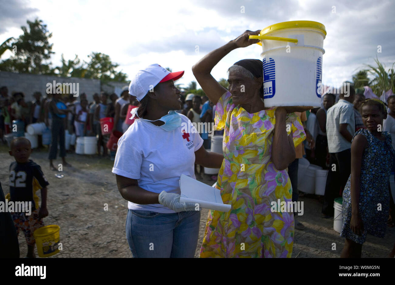 A Dominican Red Cross volunteer (L) assists in water distribution in ...