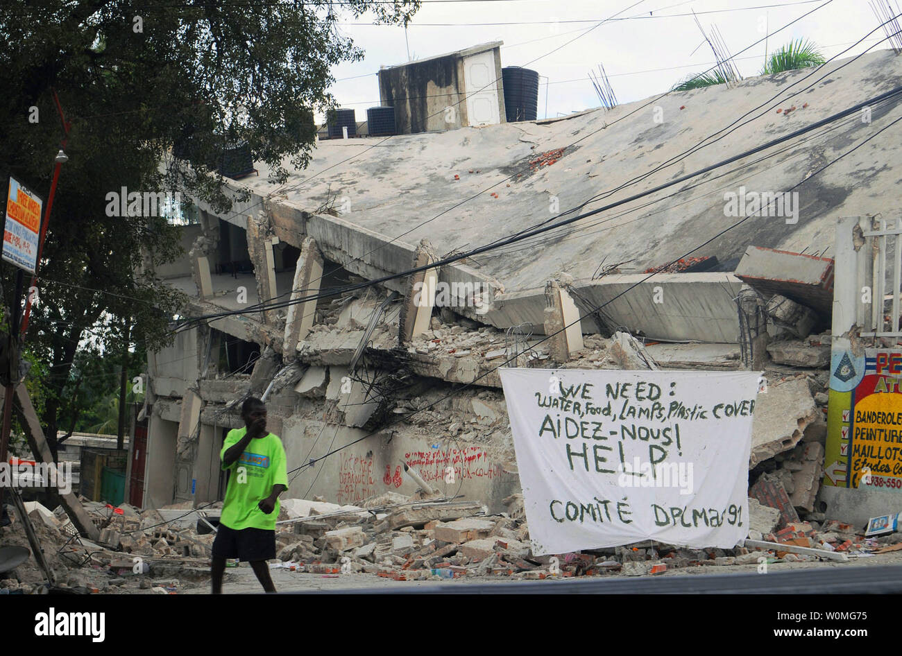 A Haitian man walks past a sign requesting help and supplies in Port-au ...
