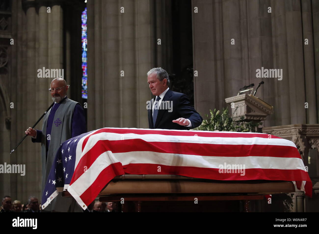 Former President George W. Bush puts his hand on the flag-draped casket ...