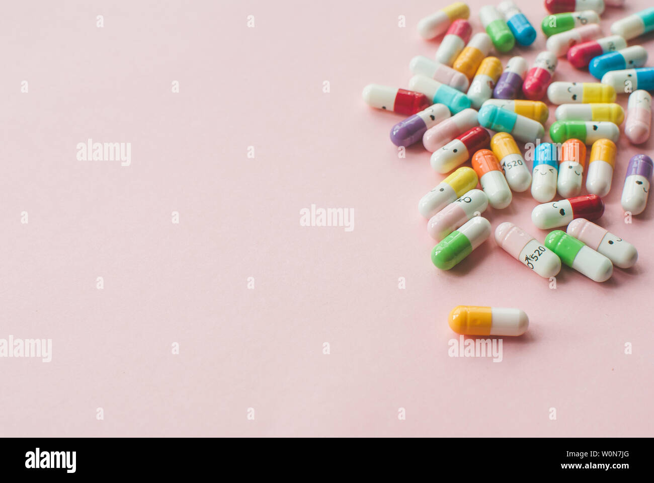 Pile of colored capsule on a pastel pink background Stock Photo - Alamy