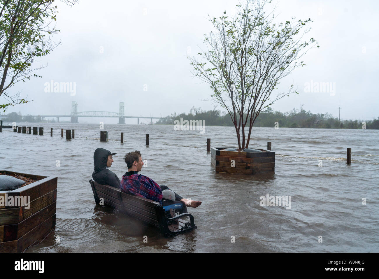 Zach Boucher and Chris Craig sit on a bench in the flooded waters edge ...