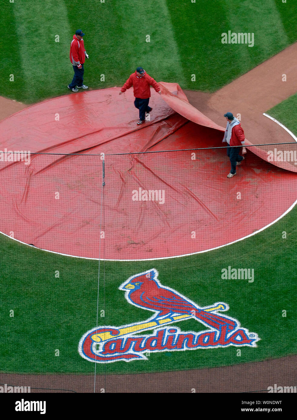 Busch Stadium grounds crew members remove the tarp covering home plate ...