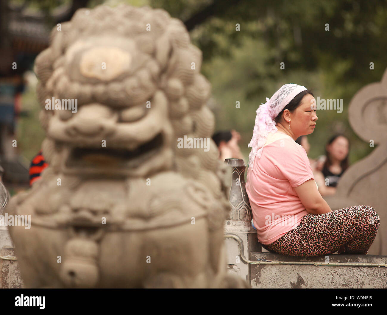 A Chinese Muslim woman relaxes in a park adorned with Chinese lion ...
