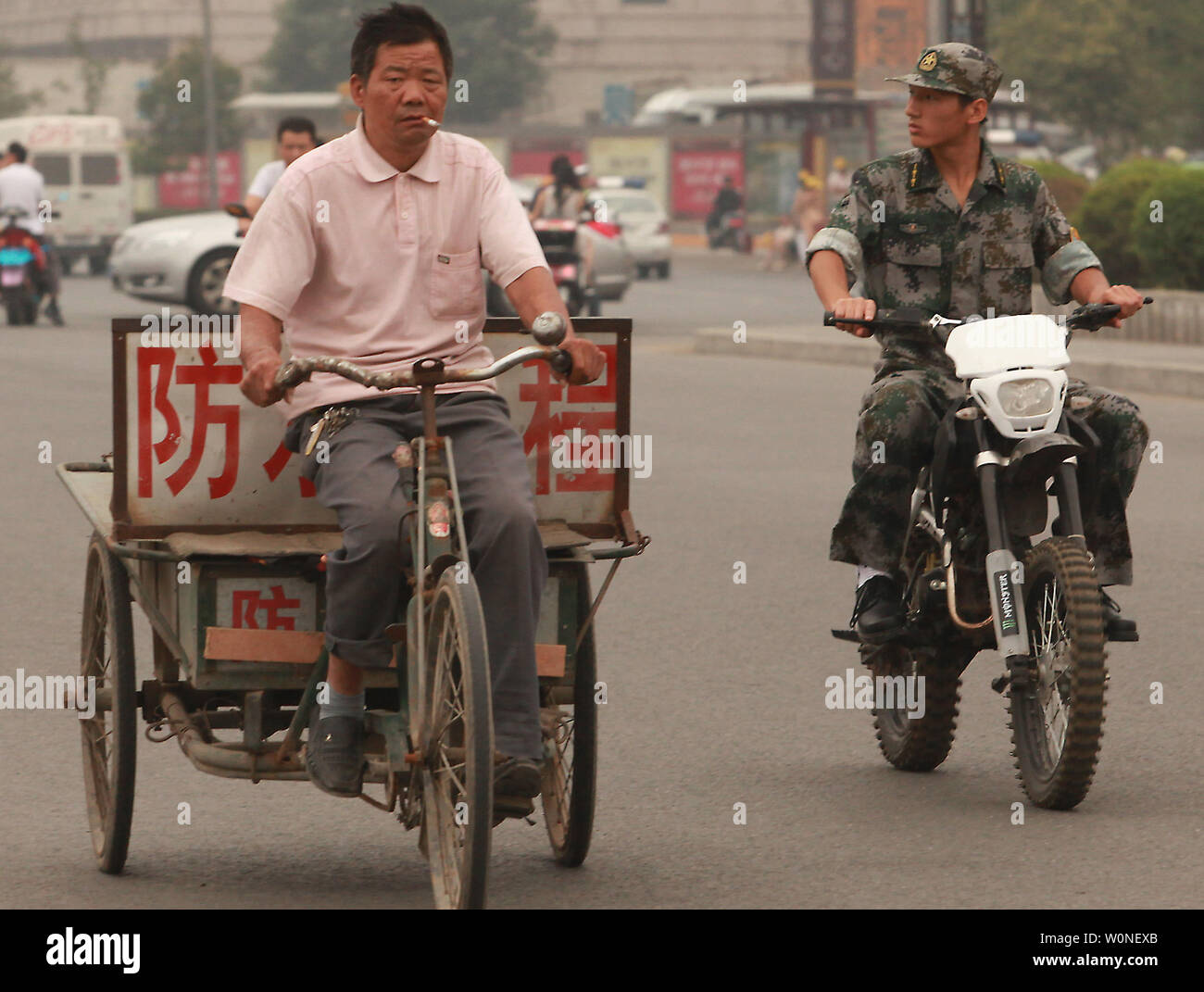A Chinese worker and soldier ride through downtown Xi'an, one of the ...