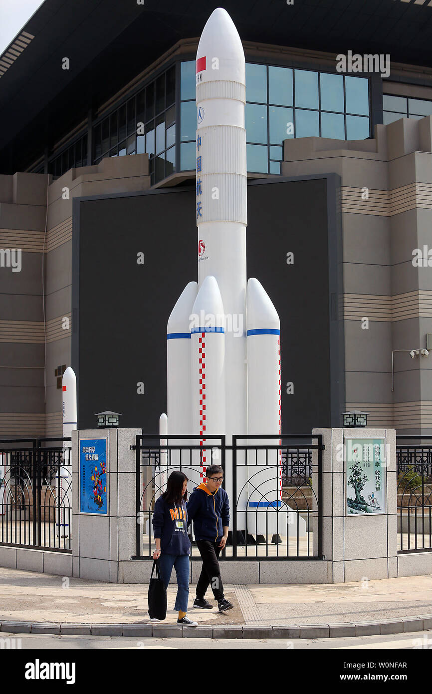 Chinese walk by a model of China's Long March rocket on display outside ...