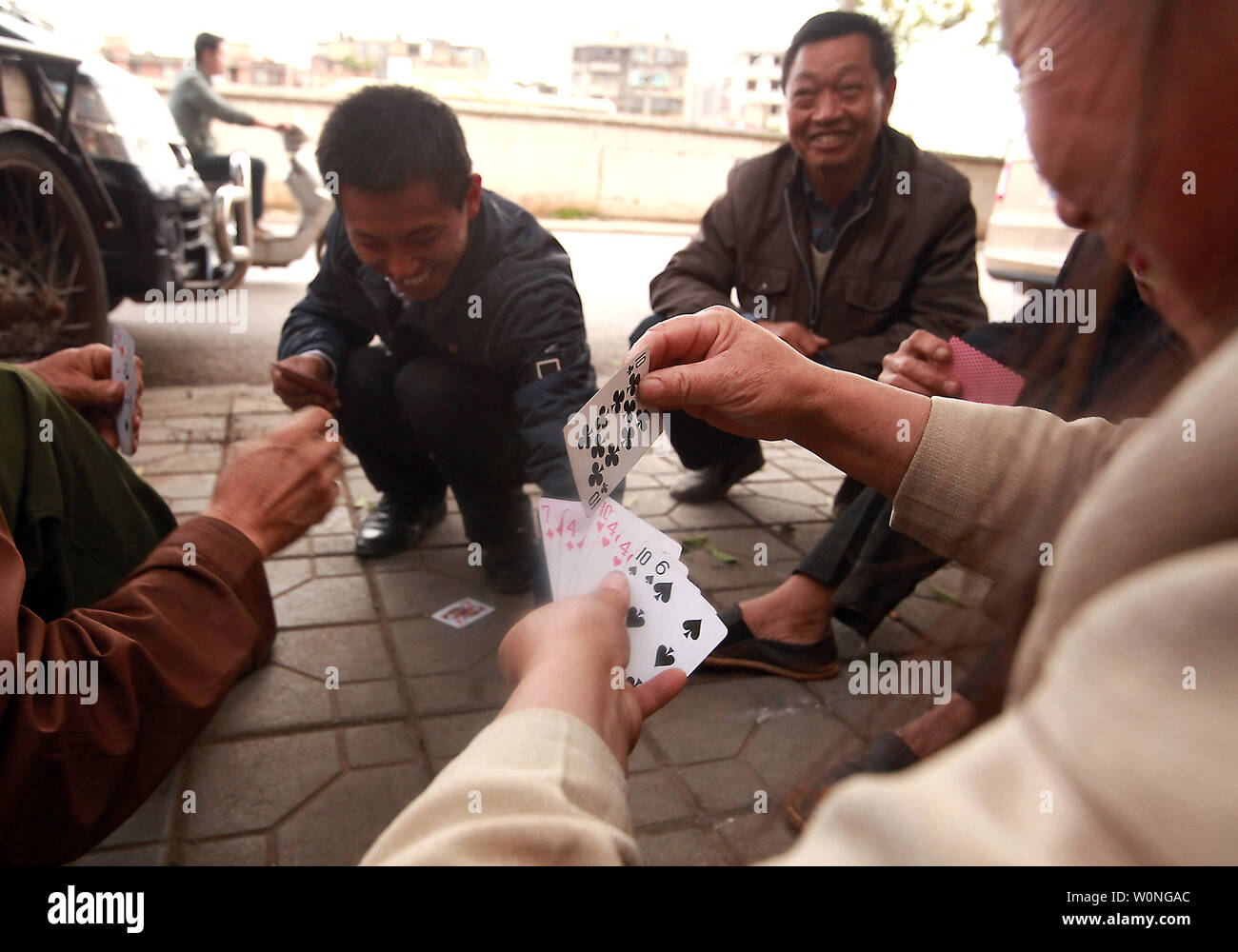 Chinese play a pick-up game of cards on a sidewalk in Kunming, the ...