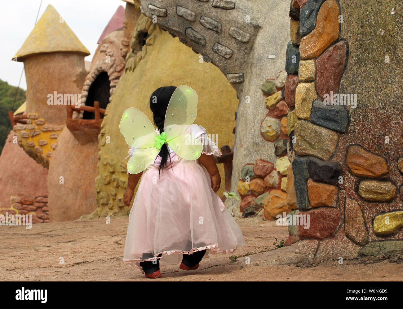 A fairy dwarf walks among 'mushroom' huts prior to the opening of a ...