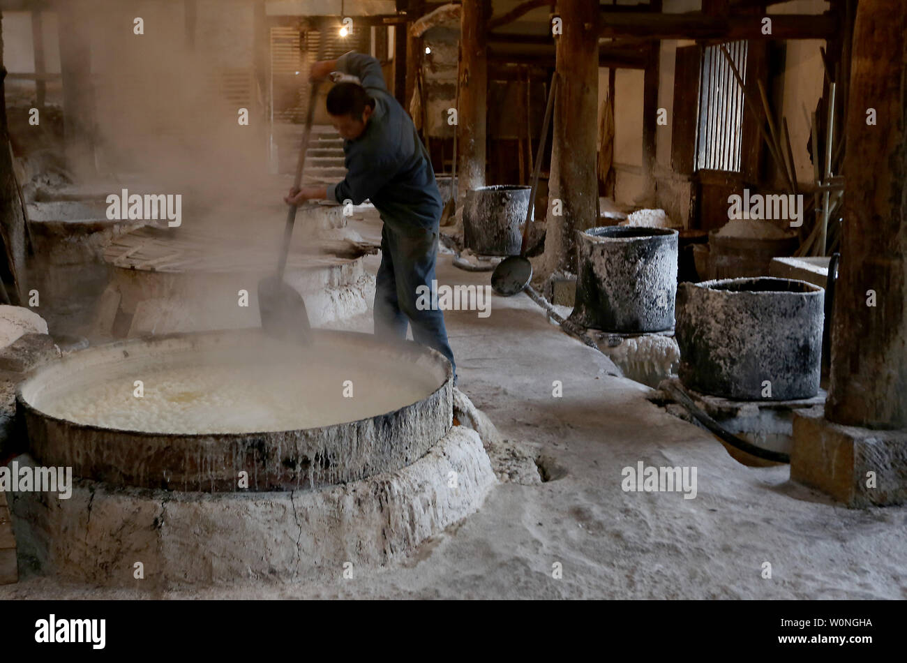 A Chinese man stirs a pool of brining salt a the Shenhai Well to be ...