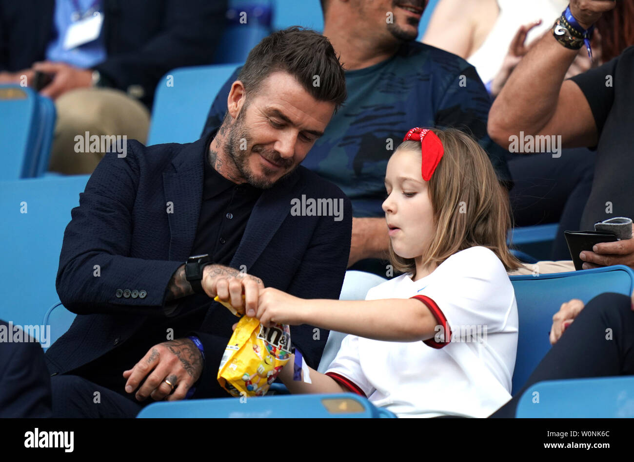 David Beckham and daughter Harper share a bag of sweets in the stands ...