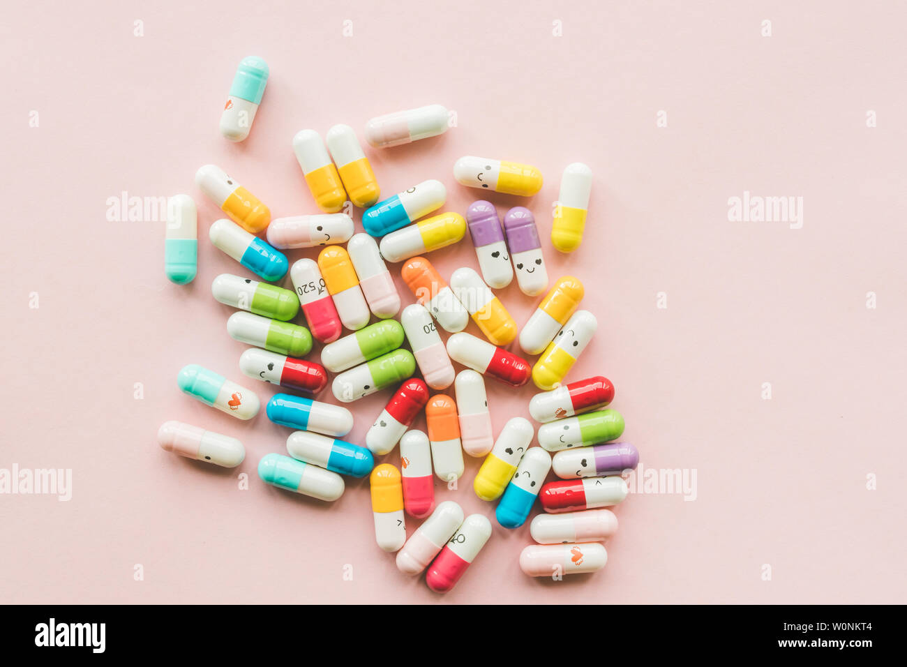 Pile of funny colored capsule on a pastel paper pink background Stock ...
