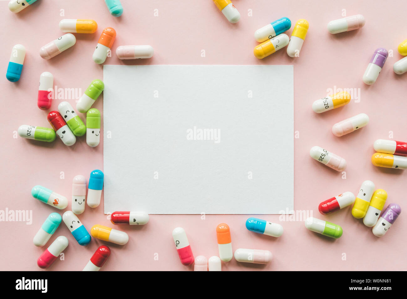 Pile of funny colored capsule on a pastel paper pink background with ...