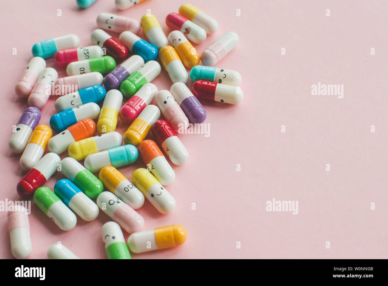 Colored capsule on a paper pink background Stock Photo - Alamy