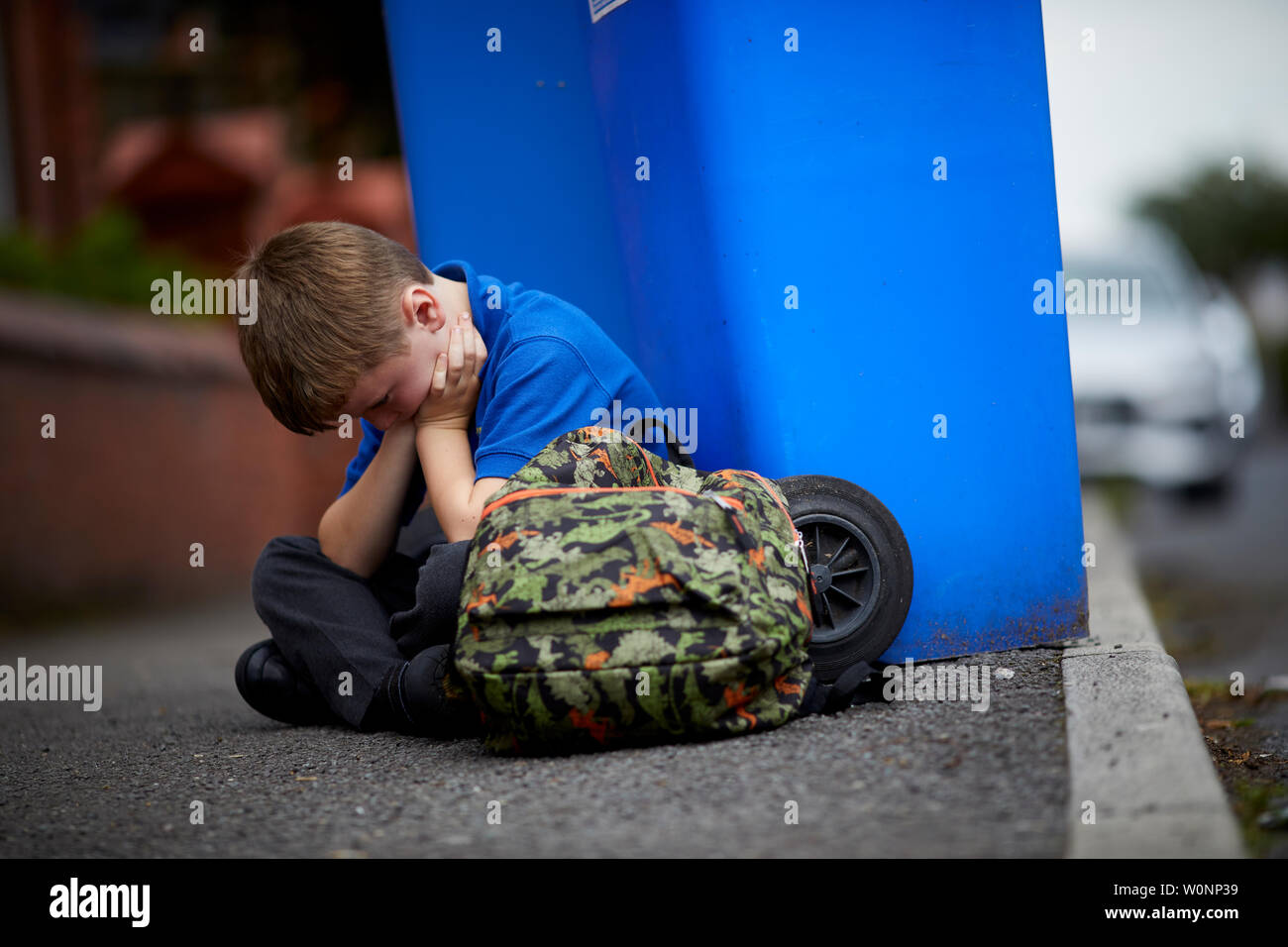 Posed by model, Troubled small child in school uniform running away and ...