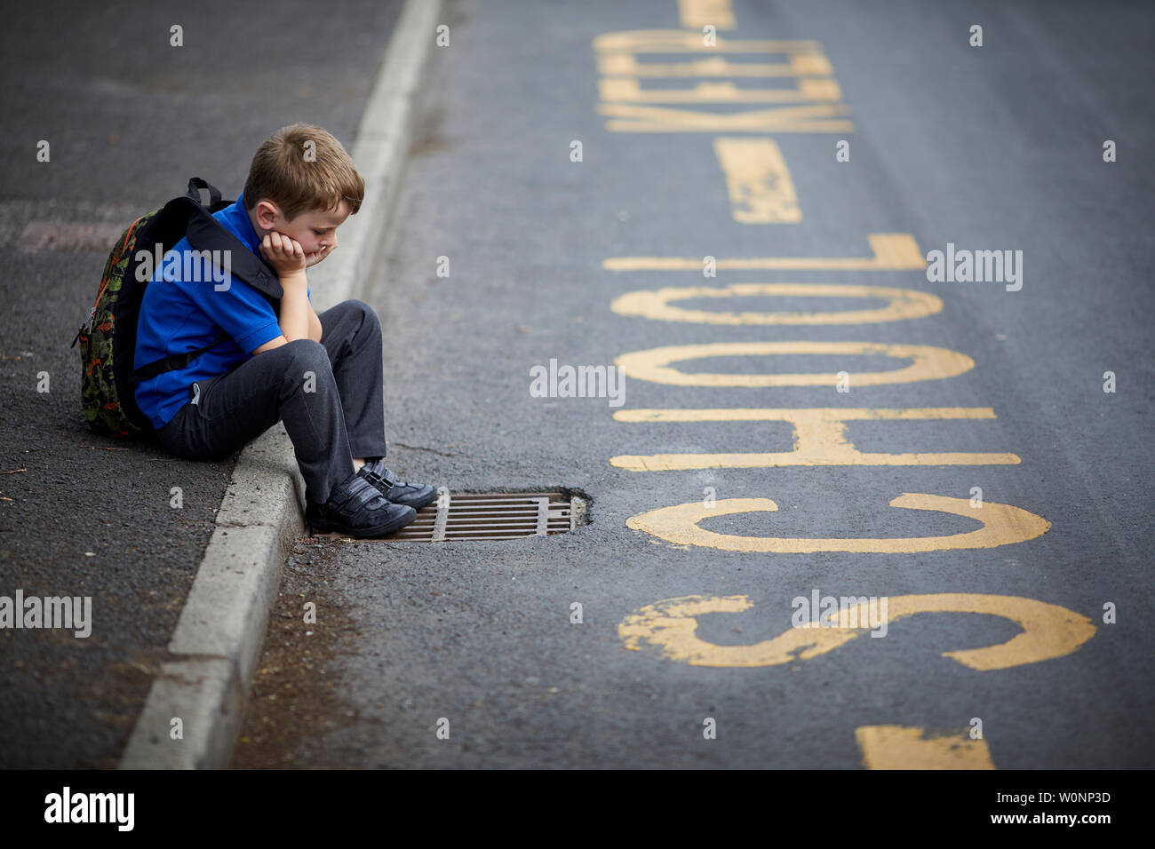 Posed by model, Troubled small child in school uniform running away and ...