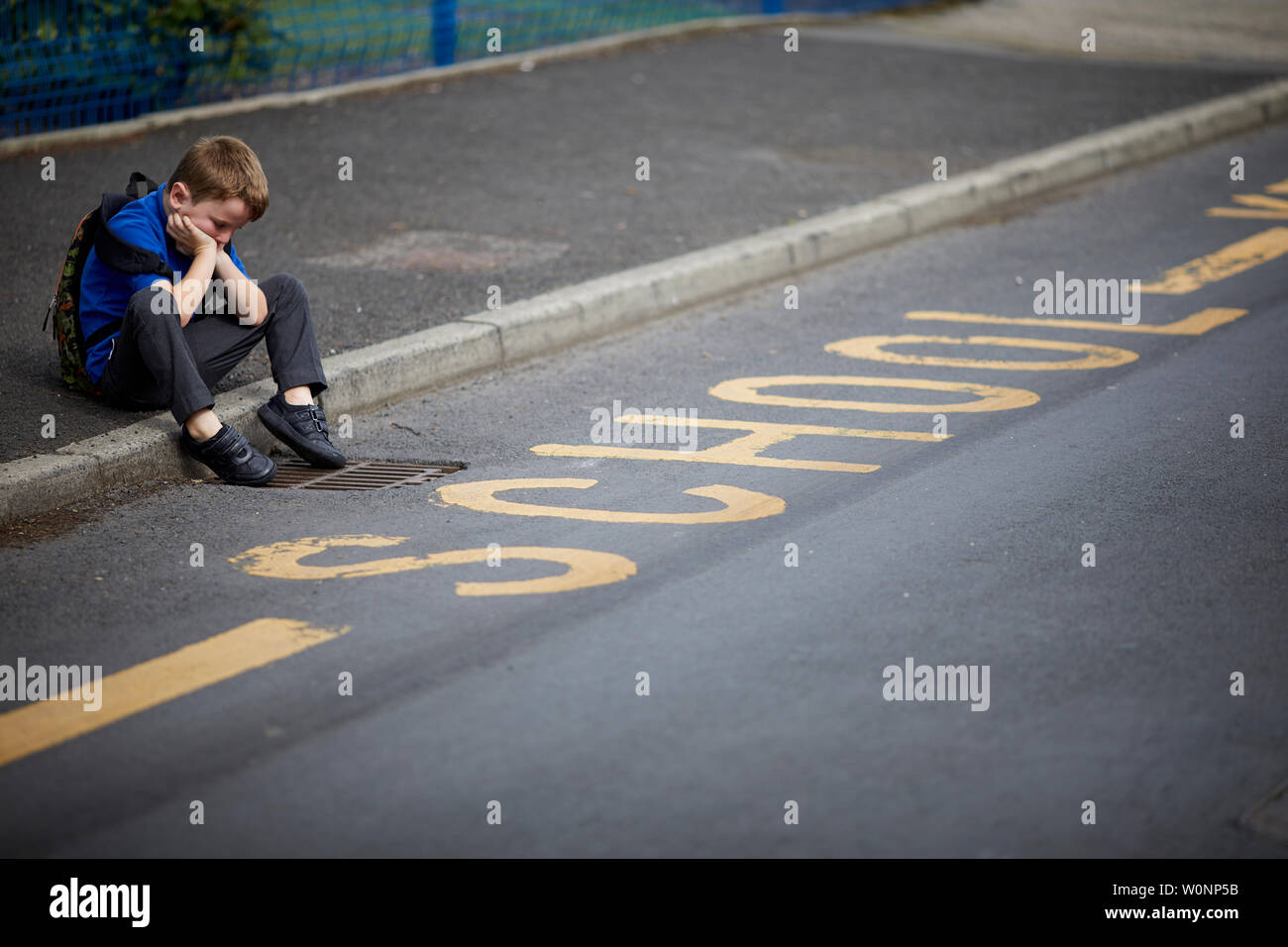 Posed by model, Troubled small child in school uniform running away and ...