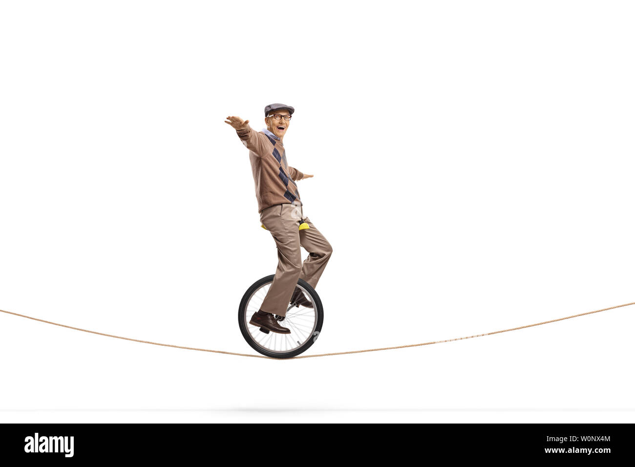 Full length shot of a senior man riding a unicycle on a rope isolated ...