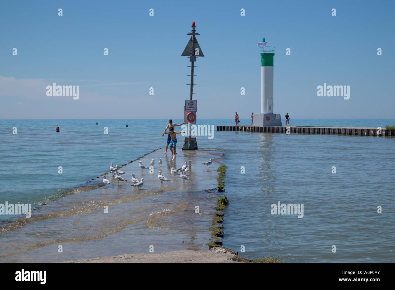 Two lads have fun by walking on a very slippery dam at Kincardine beach ...