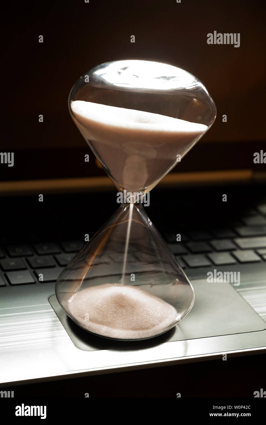 An hourglass sits on a laptop computer Stock Photo - Alamy