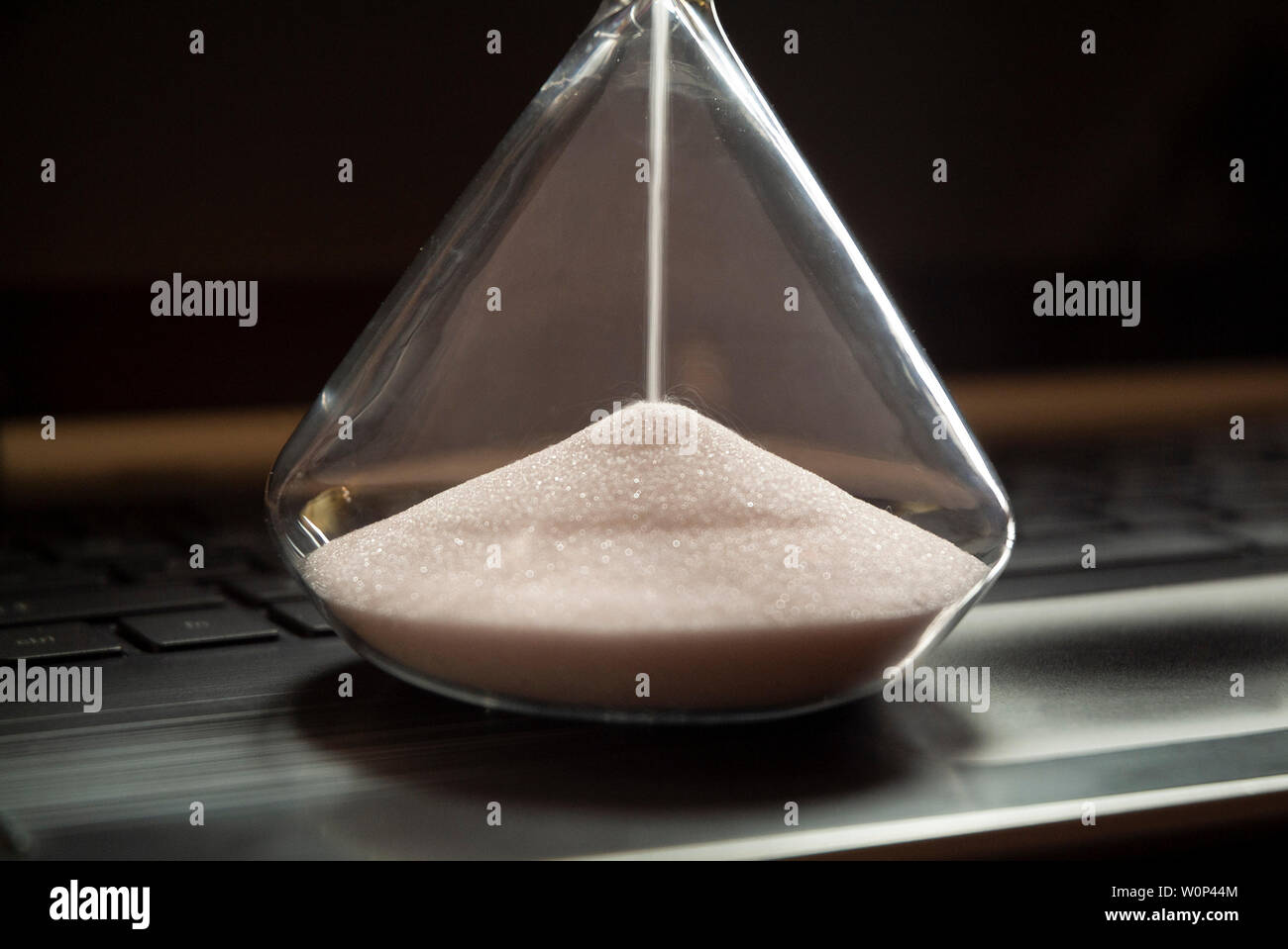 An hourglass sits on a laptop computer Stock Photo - Alamy