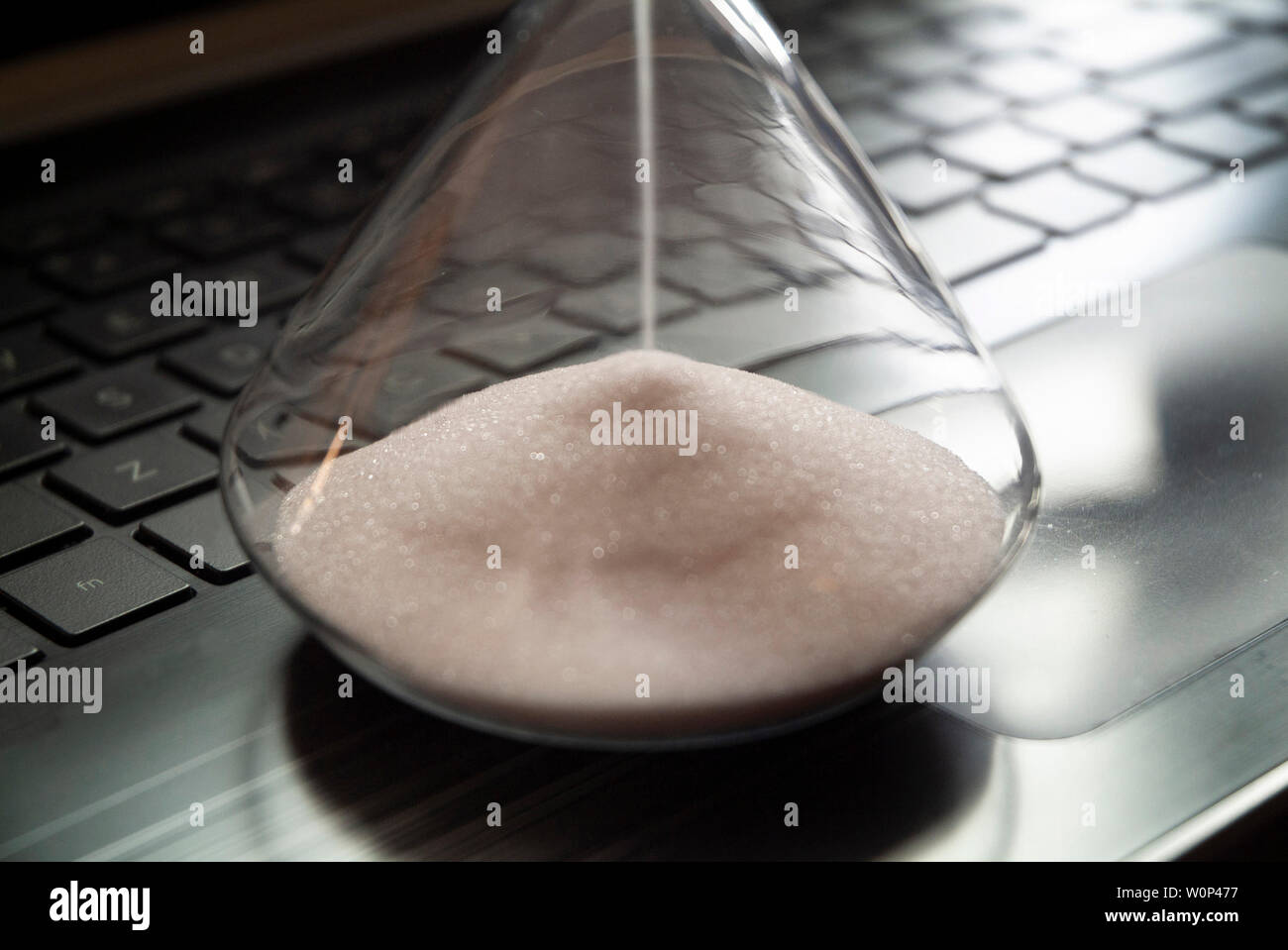 An hourglass sits on a laptop computer Stock Photo - Alamy