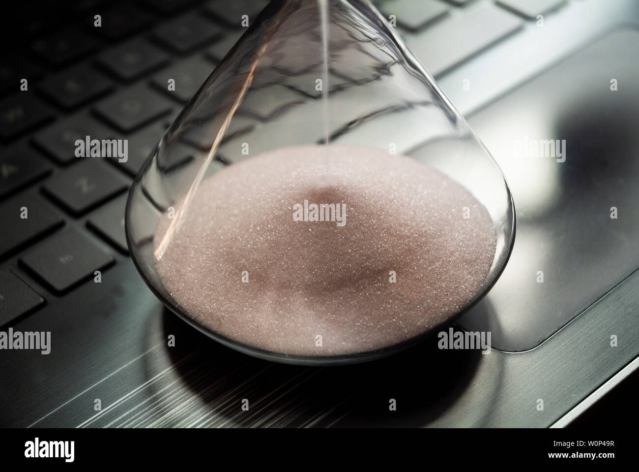 An hourglass sits on a laptop computer Stock Photo - Alamy