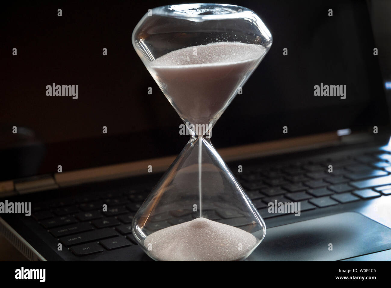 An hourglass sits on a laptop computer Stock Photo - Alamy