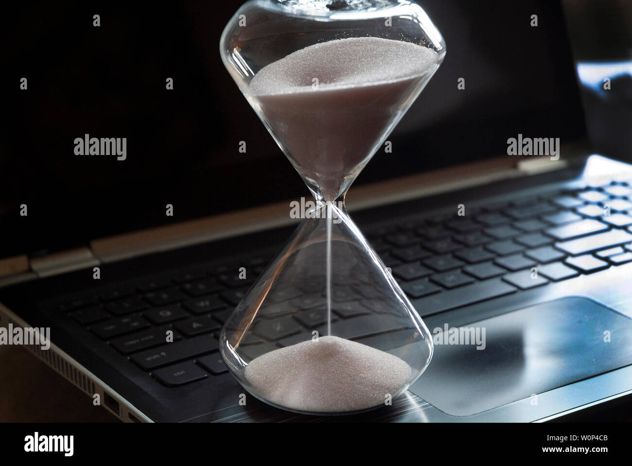 An hourglass sits on a laptop computer Stock Photo - Alamy