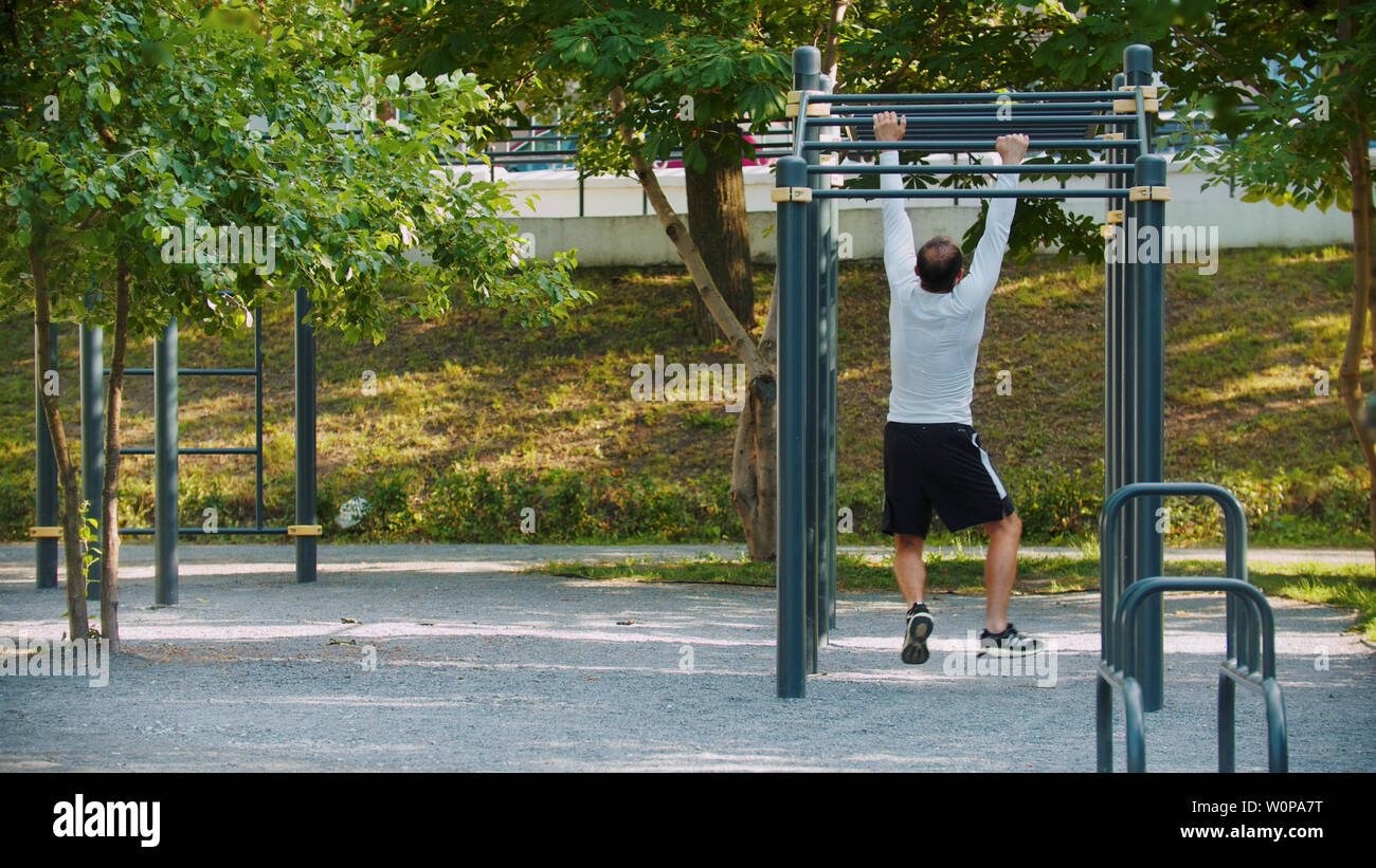 An athletic man hanging on the bar - Mid shot Stock Photo - Alamy
