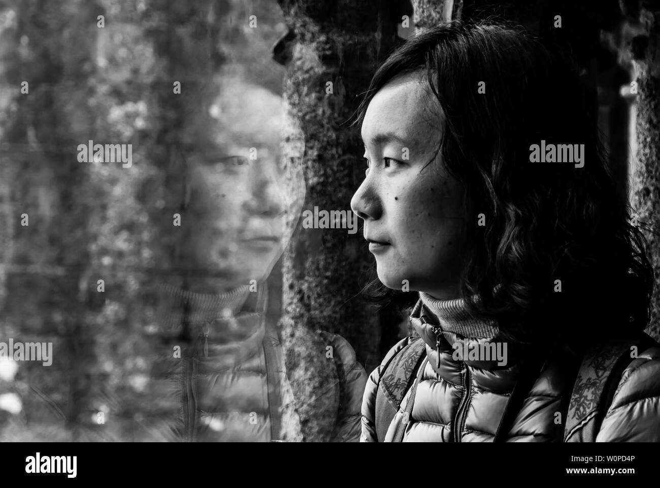 Girl gazing at the window which reflects her face in Mont Saint Michel ...