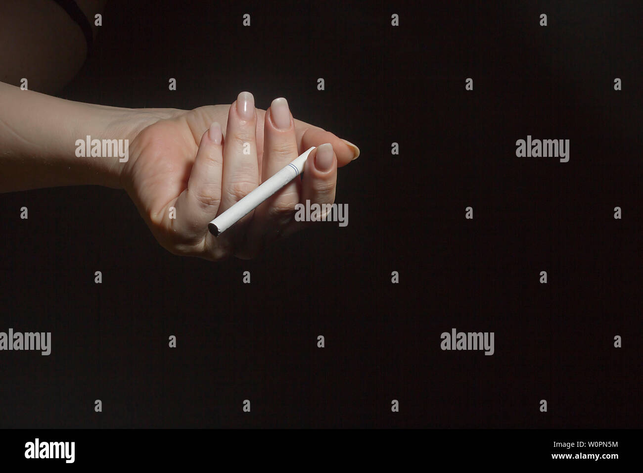 Female hand with an unlit cigarette on a black background Stock Photo ...