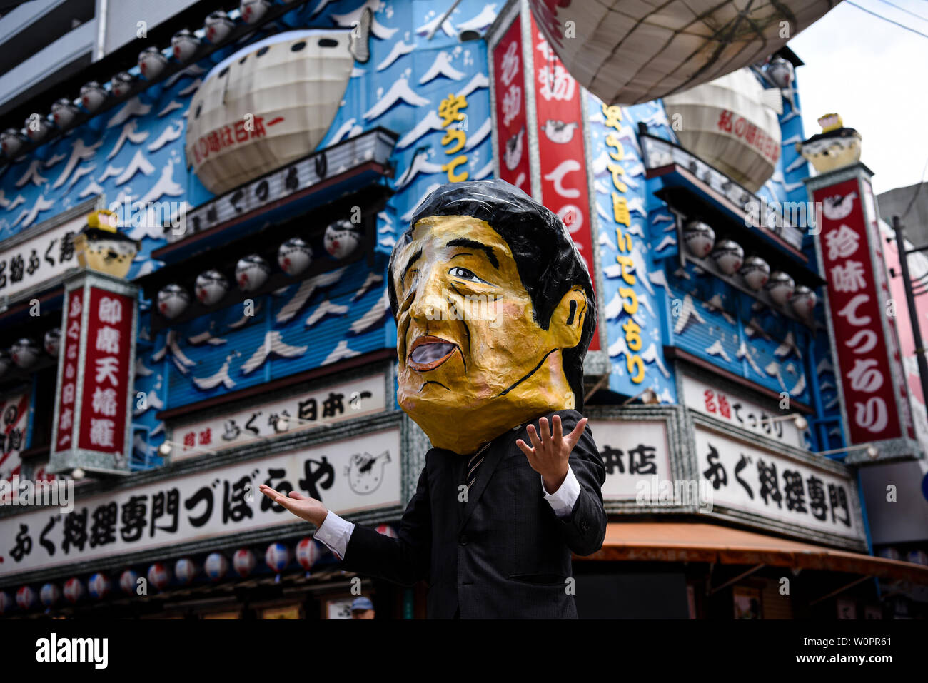 Osaka, Japan. 28th June, 2019. A protestor wears a mask of Japanese ...