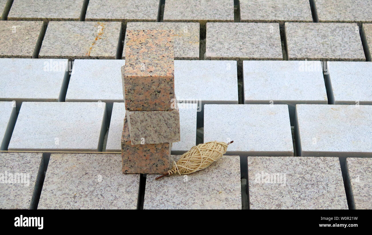 Stacked paving stones and roll of guide string on newly laid road ...