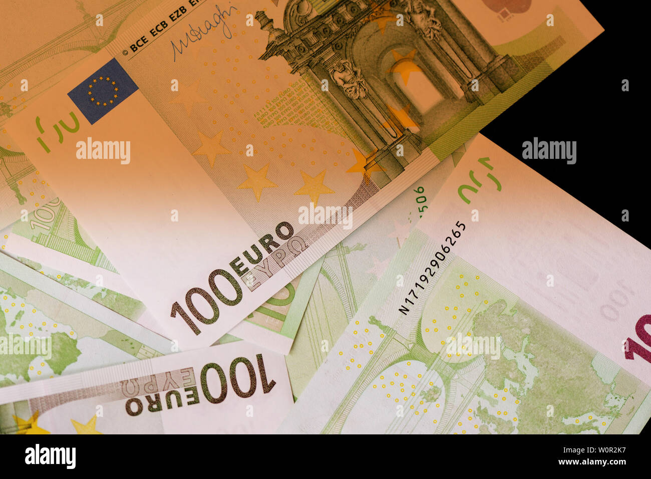 One hundred euro notes on a dark background close up. Brown color toned ...