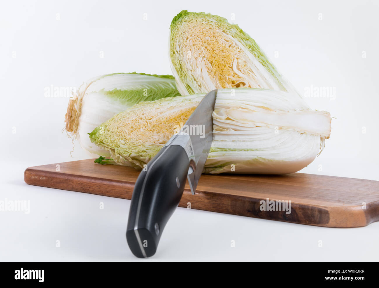 Two half of Chinese cabbage with knife on chopper board isolated on ...