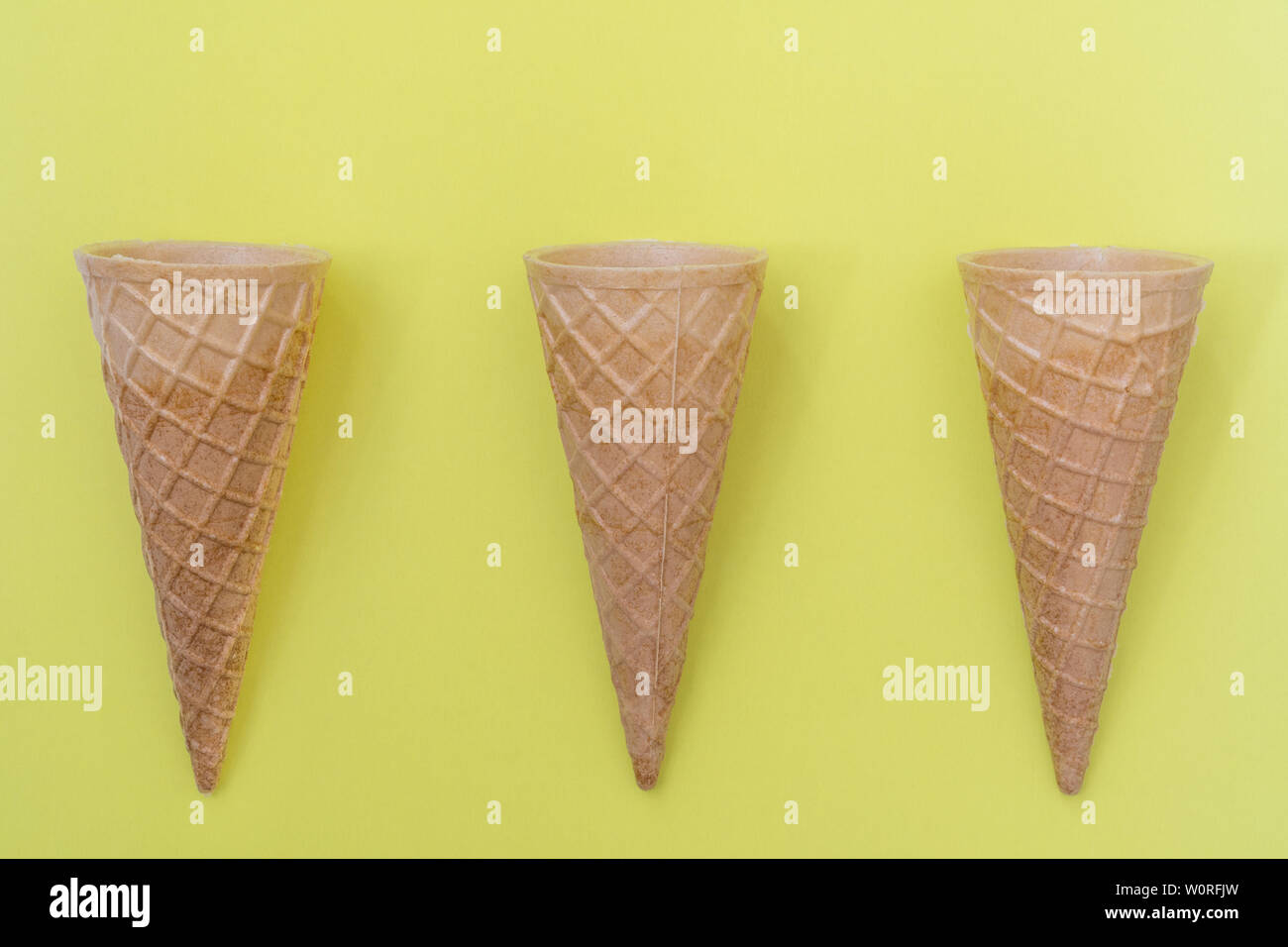 Three sweet wafer cones on yellow background Stock Photo - Alamy