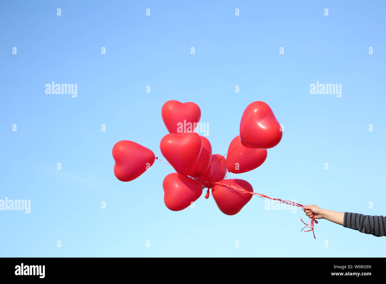 Hand holding a red balloon floating in the air Stock Photo - Alamy