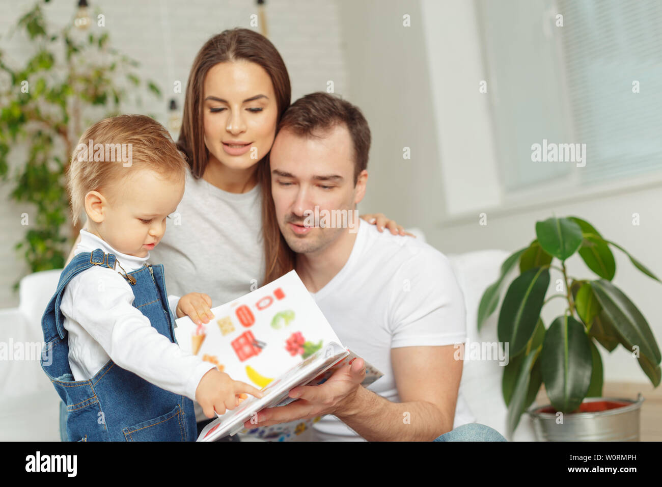 Happy family reading a book together Stock Photo - Alamy