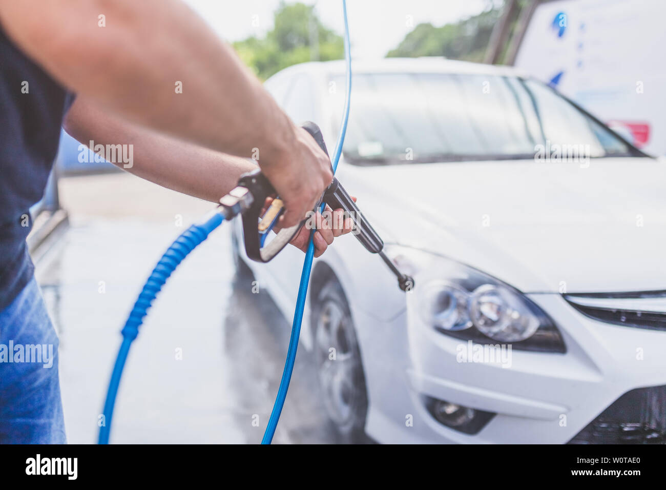 Close up of man washing his car with pressurized water in car wash ...