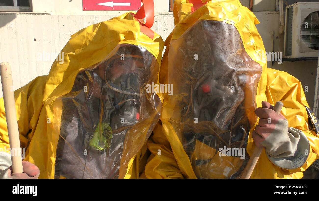 Two firefighters dressing protective suites ready to clean victims from ...