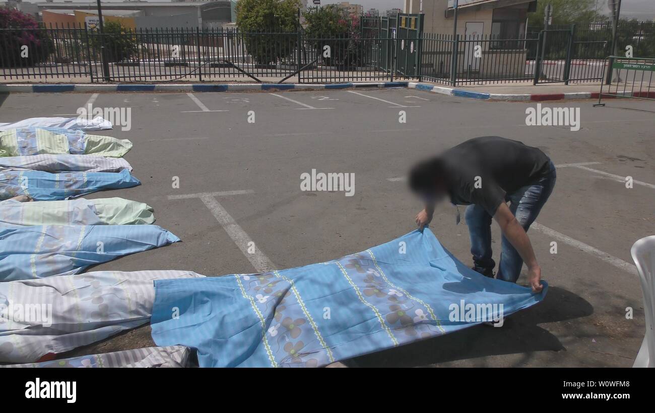 A man covers a dead corpse of mannequin, wrapped in hospital sheets ...