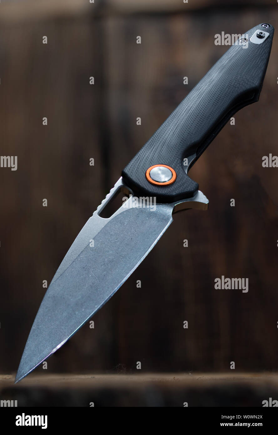 Folding knife on a wooden background. Knife at an angle. The vertical ...