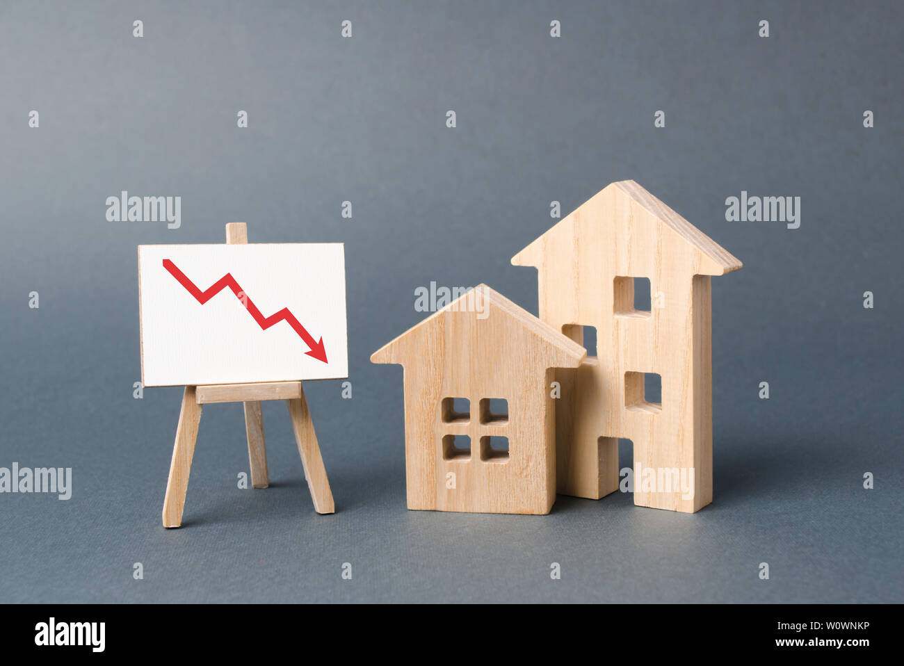 Two wooden houses and a poster with a symbol of falling value. concept ...