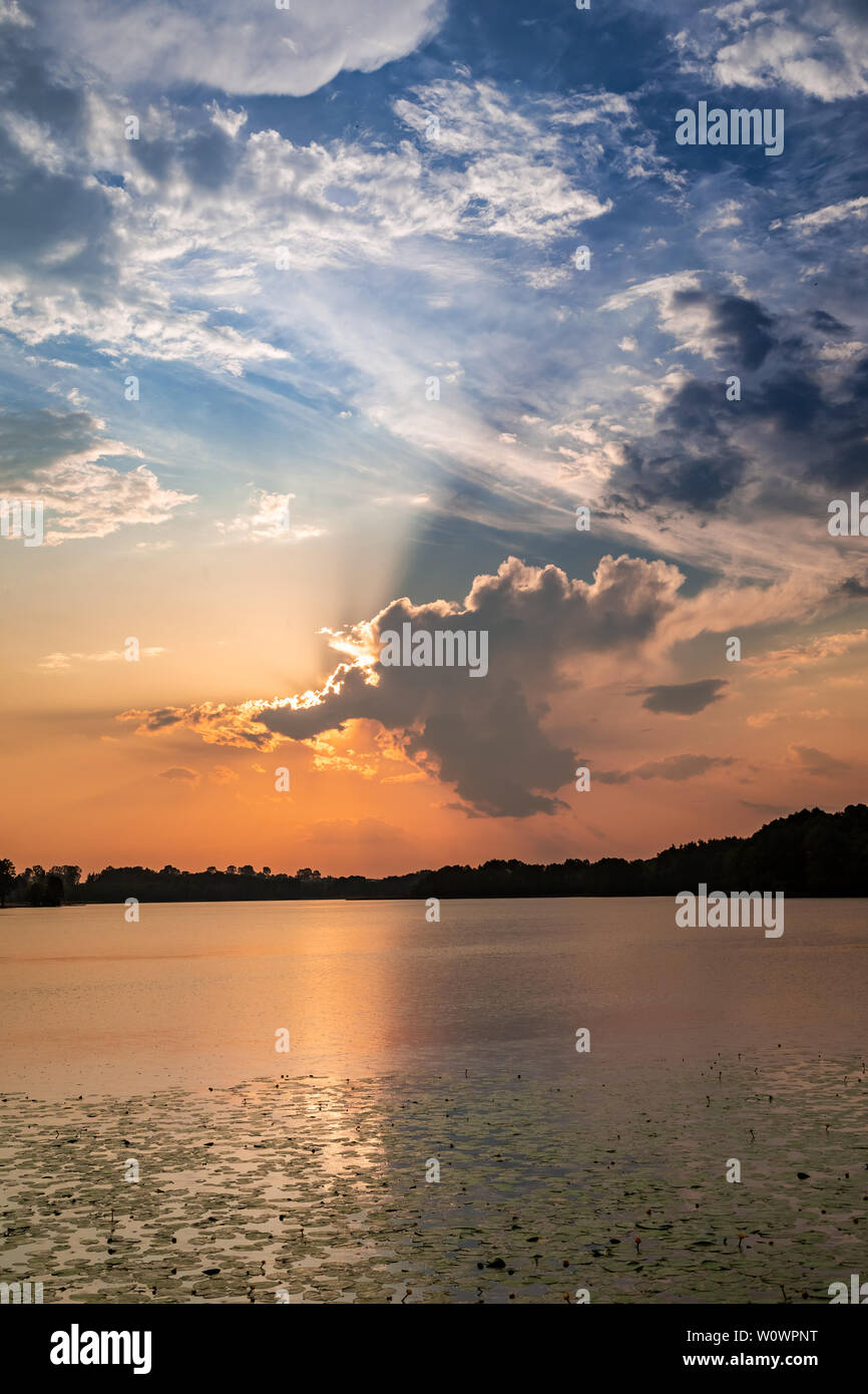 Calm sunset at lake with sun rays in clouds Stock Photo - Alamy