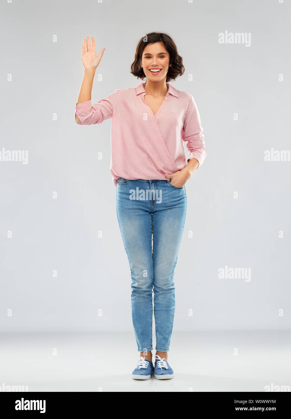 young woman in shirt and jeans waving hand Stock Photo - Alamy