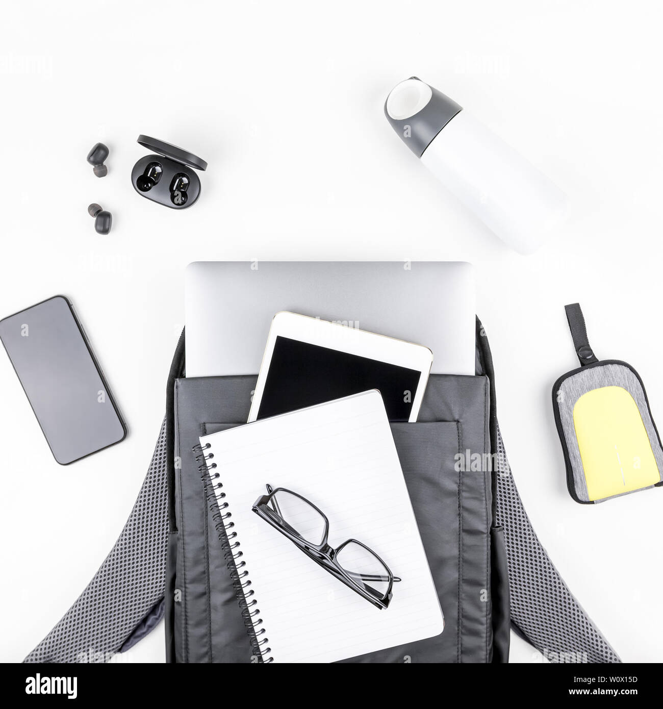 Creative top view flat lay of open backpack with laptop and tablet ...